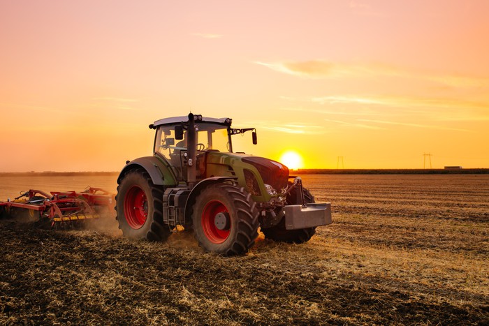 Fototapete Traktor auf dem Gerstenfeld bei Sonnenuntergang. • Pixers ...